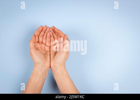 Empty cupped palm hands, keeping hands together on light blue ...