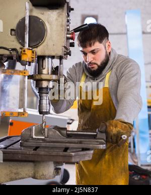 Workman drilling metal parts on stationary machine Stock Photo - Alamy
