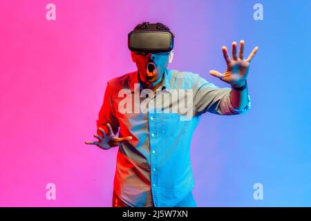Scared young man playing game in virtual reality glasses Stock Photo ...