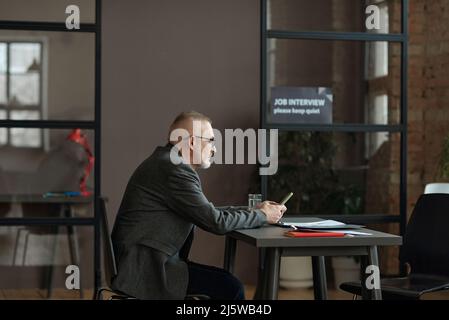 Serious mature candidate for job using mobile phone while sitting at ...