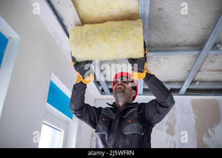 Worker installing glass wool Stock Photo - Alamy
