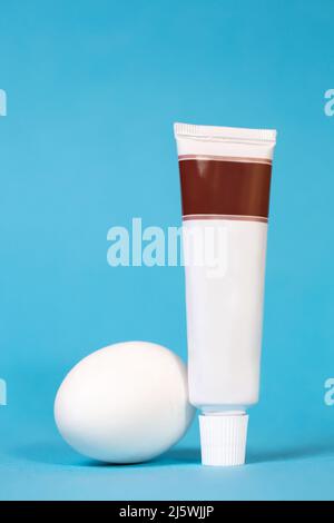 an egg and a tube of toothpaste without a logo on a blue background ...