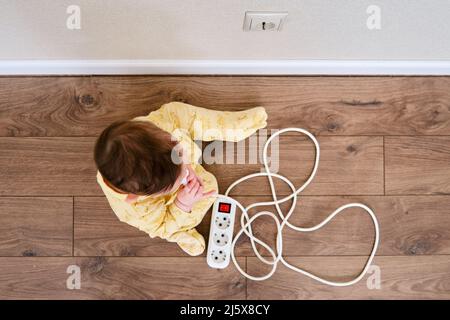 Toddler baby boy plays with electric wires while sitting on the floor ...