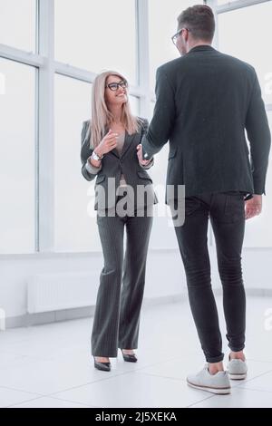 smiling employees discuss something standing in the office corridor ...