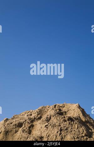 Mound of fine sand against blue sky background at construction site ...