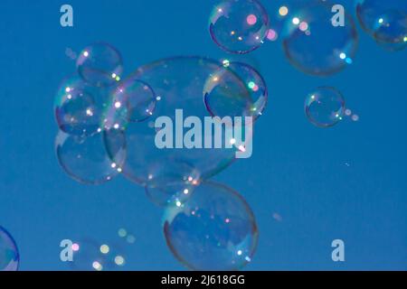 Gigantic soap bubbles shimmer and glimmer in the sun as colorful kids ...