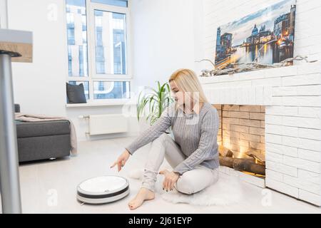 Young woman using automatic vacuum cleaner to clean the floor Stock ...