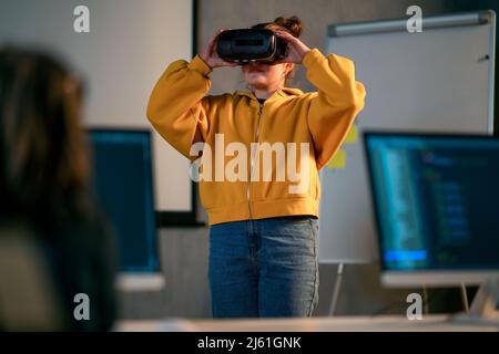 Schoolgirl wearing virtual reality goggles at school in computer ...