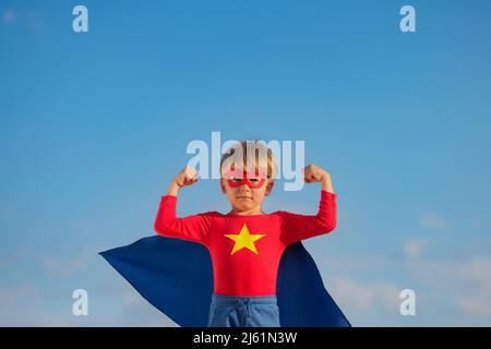Superhero child playing outdoor. Super hero kid against blue summer sky ...
