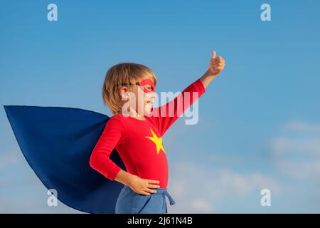 Superhero child playing outdoor. Super hero kid against blue summer sky ...