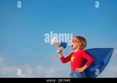 Superhero child shouting through loudspeaker outdoor. Super hero kid ...