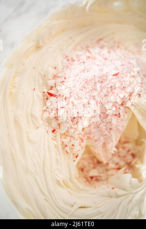 Whisking buttercream frosting in a glass mixing bowl with an electric ...