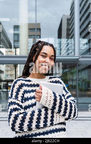 Smiling businesswoman with tablet PC standing in office Stock Photo - Alamy