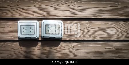 Waterproof electrical sockets installed outdoors on dark wooden walls ...