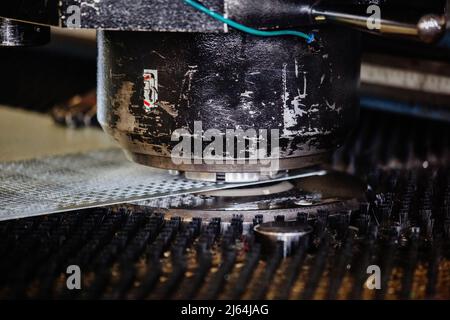 CNC punching and nibbling machine and perforated steel sheet, close up ...