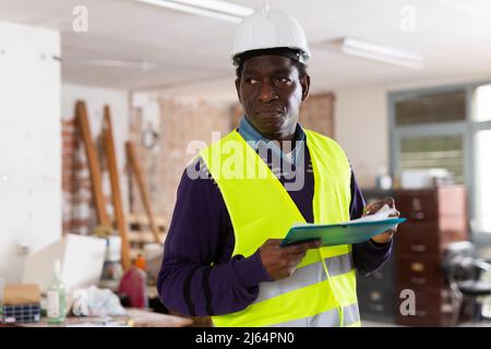 Strict building inspector standing with papers at construction site ...