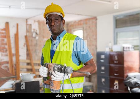 Professional builder holding pneumatic chipping hammer in building ...
