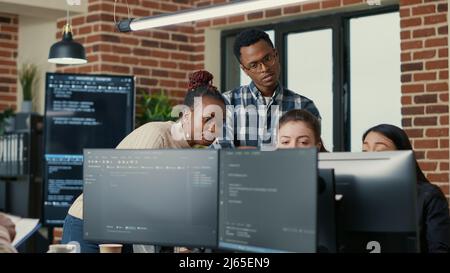Junior developers collaborating on group project compiling algorithm asking senior programer for ...