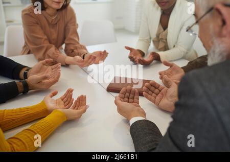 Diverse group of people praying to Lord sitting together around table ...