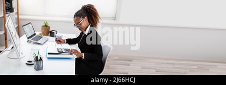 Young Businesswoman Calculating Bill With Computer And Laptop On Desk ...