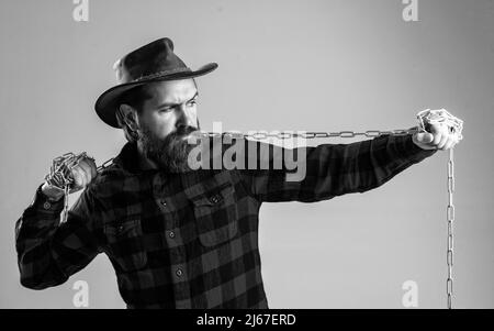 Cowboy man with beard and mustache pull steel chain, routine at ranch ...