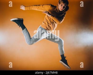 Flexible athletic man during an intense dance exercise while jumping ...