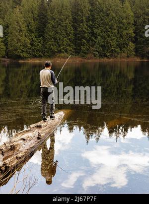 A man is fly fishing or spinning on a mountain lake. Recreational ...
