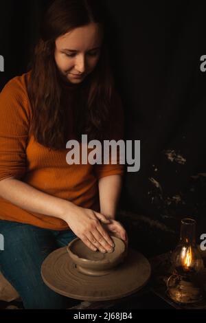 A ceramist makes a plate. Woman in an apron works in a pottery workshop ...