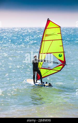 A wind surfer with a bright green sail on a choppy blue sea Stock Photo ...