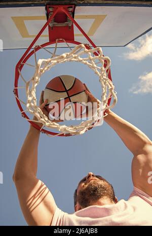 man dunking basketball ball through net ring with hands, copy space ...