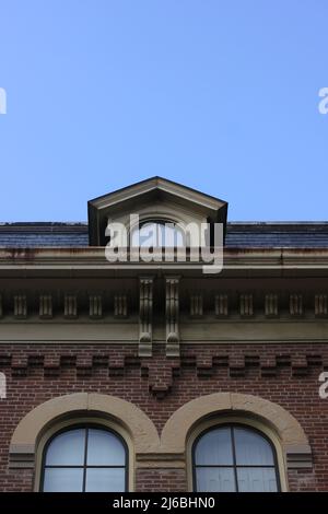 A traditional colonial attic window high on the roofline in high ...