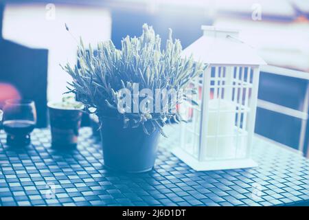 Modern house terrace with lantern, glasses and plant on the table. High ...