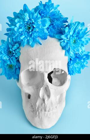 Human skull with flowers on blue background Stock Photo - Alamy