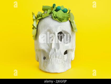 Human skull and handmade paper flowers on lilac background with space ...