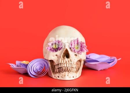 Human skull and handmade paper flowers on lilac background with space ...