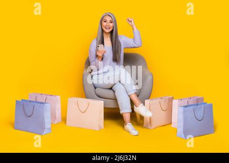 Photo of shiny lucky age woman wear blue cardigan glasses rising fist ...