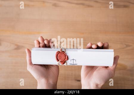 top view of rolled contract stamped with wax seal in hands of cropped ...