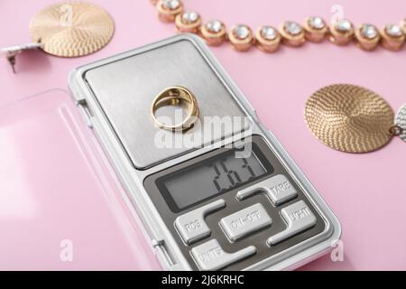 Jewelry scales with ring on pink background Stock Photo - Alamy