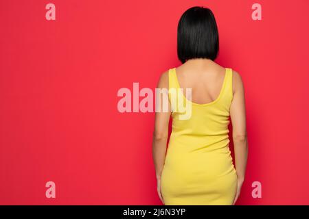 Brunette woman standing over yellow background thinking worried about a ...