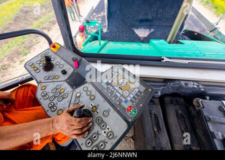 Worker, operator is controlling tarmac road laying machine with ...