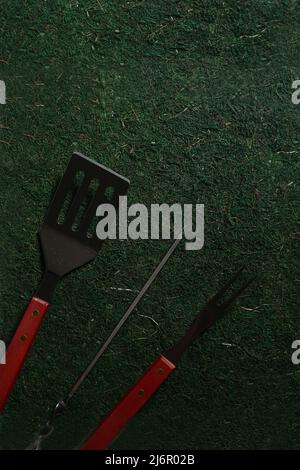 BBQ instruments kit - tongs, spatula, fork - close up isolated on green ...
