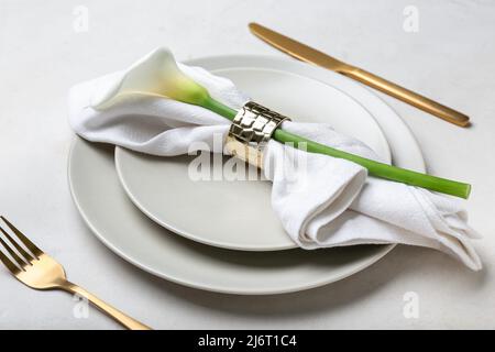 Cutlery, napkin and beautiful calla lily on light background with space ...
