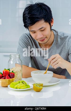 Asian man eating oatmeal for breakfast Stock Photo - Alamy