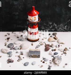 A small decorative lighthouse with sea shells and stones on a dark ...