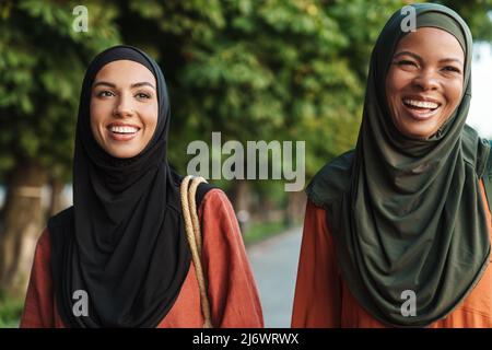Multiracial muslim women laughing while walking together outdoors Stock ...