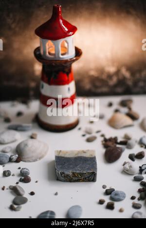 A small decorative lighthouse with sea shells and stones on a dark ...