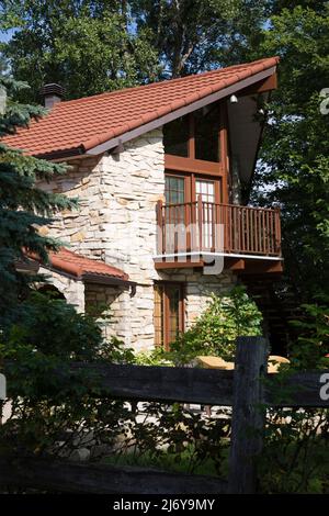 Cut-stone home facade and landscaped front yard with wicker furniture ...