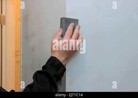 Worker sanding the drywall mud using sand trowel during renovation the ...