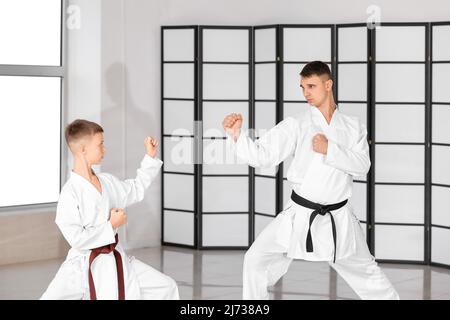 Boy practicing karate with instructor in dojo Stock Photo - Alamy