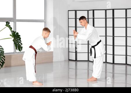 Boy and sensei performing ritual bow before practicing karate on yellow ...